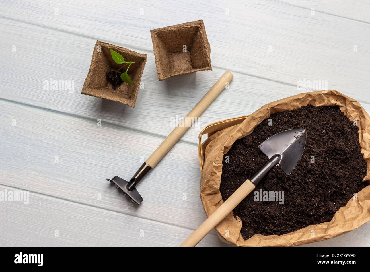 Soil in a paper bag and a shovel on top. Rakes and peat pots. Flat lay ...