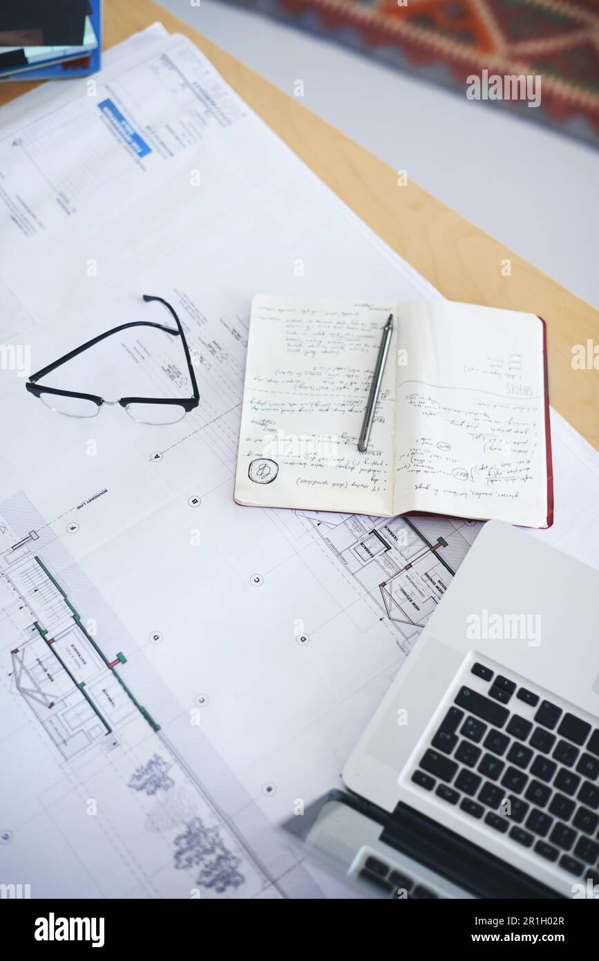 Notebook, laptop and blueprint on desk above for architecture planning ...
