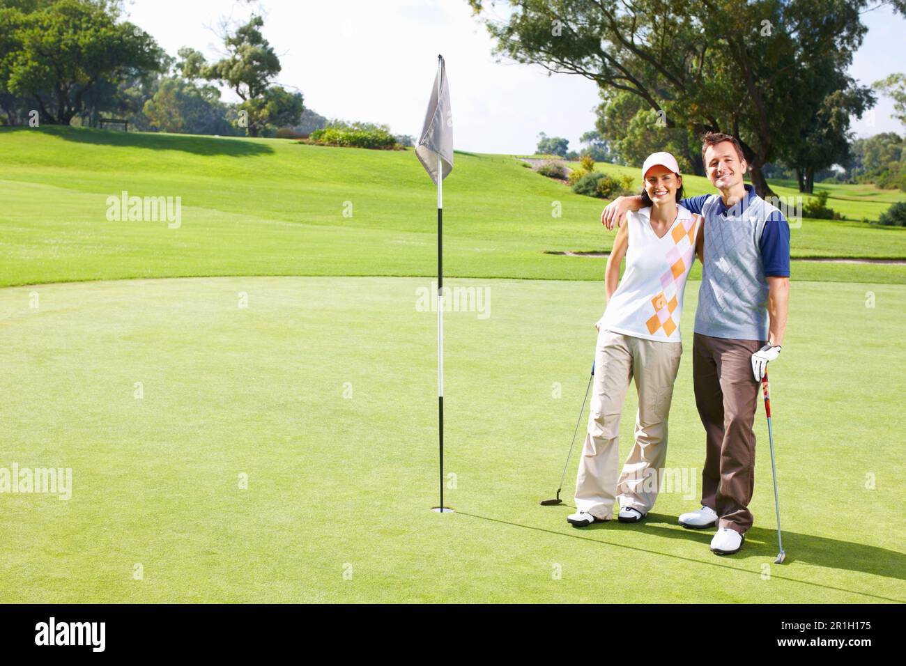 Golfing couple standing on the putting green. Full length of golfing ...