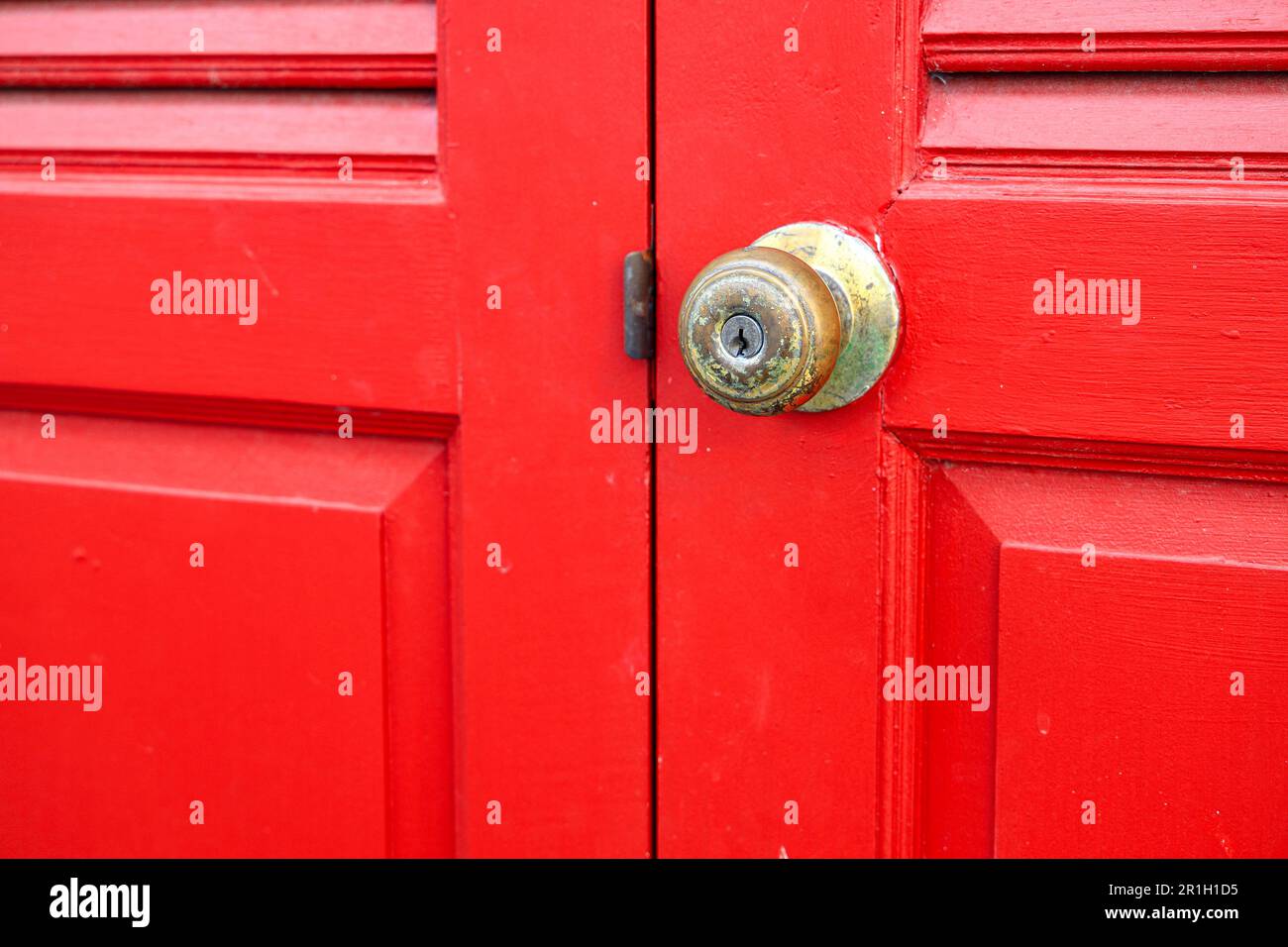 Old red wooden door with grill, brass doorknob or handle in lock ...