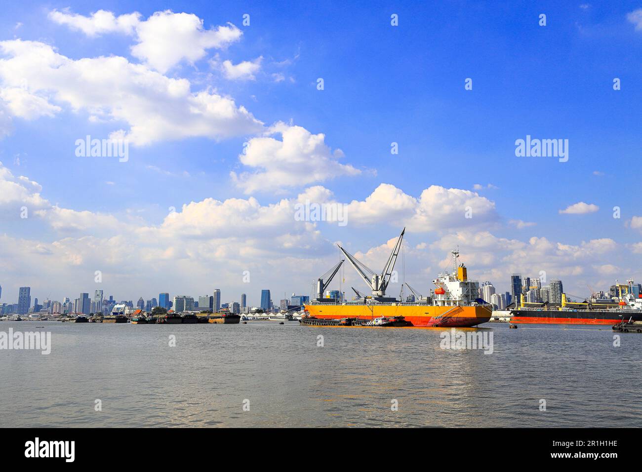 cargo ship or Ocean barge with cranes at international port, with CBD ...