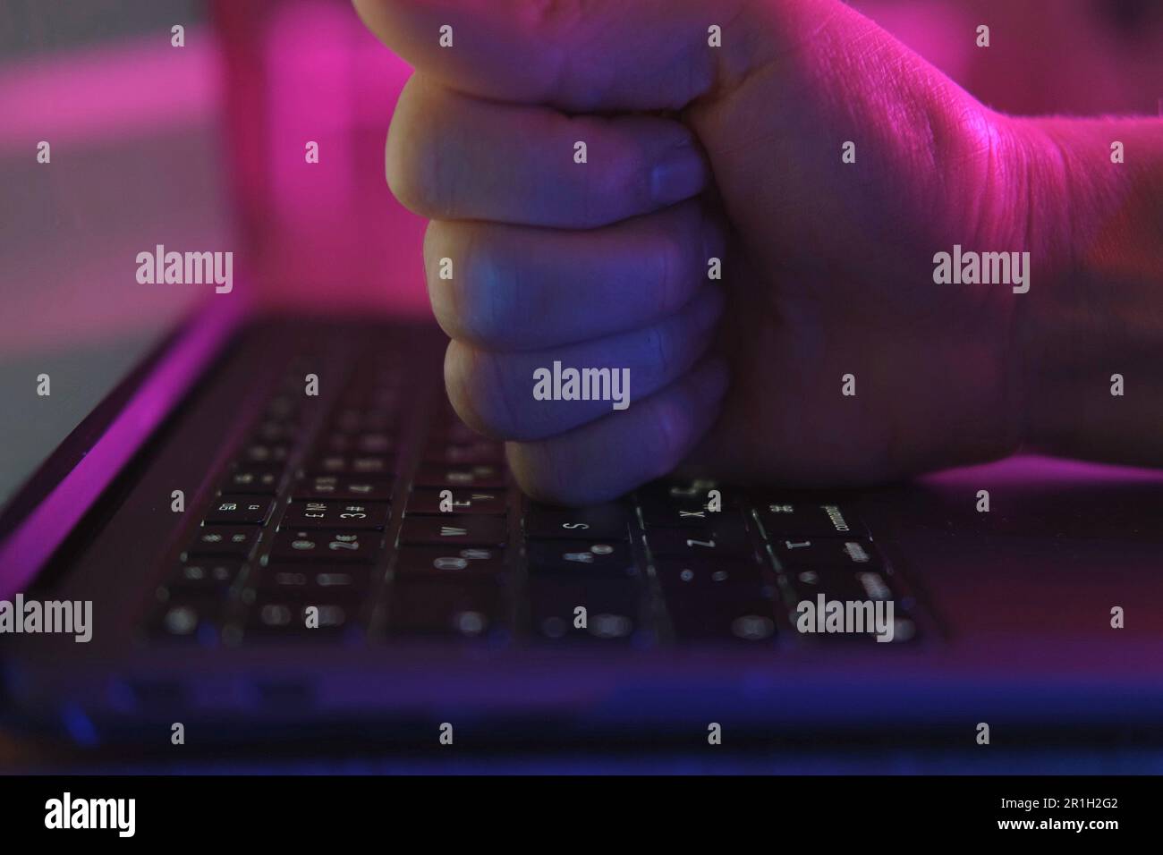 Human fist bump on the keyboard of laptop. Neon pink blue light ...