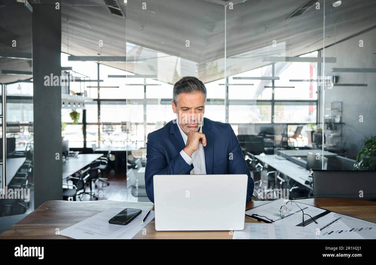 Busy serious business man ceo looking at laptop thinking in modern ...