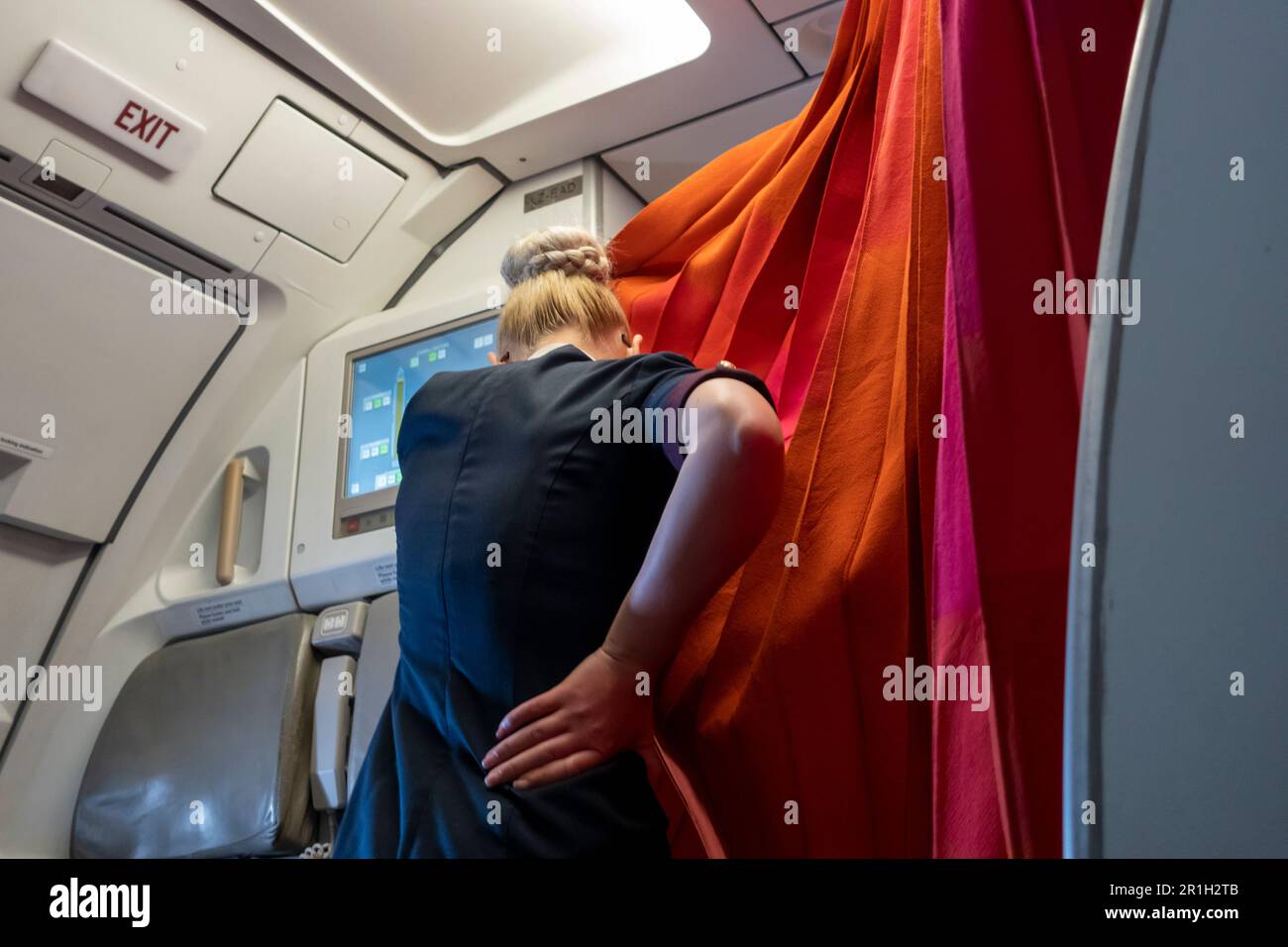 An air stewardess covers the entrance to the cockpit as a pilot enters ...