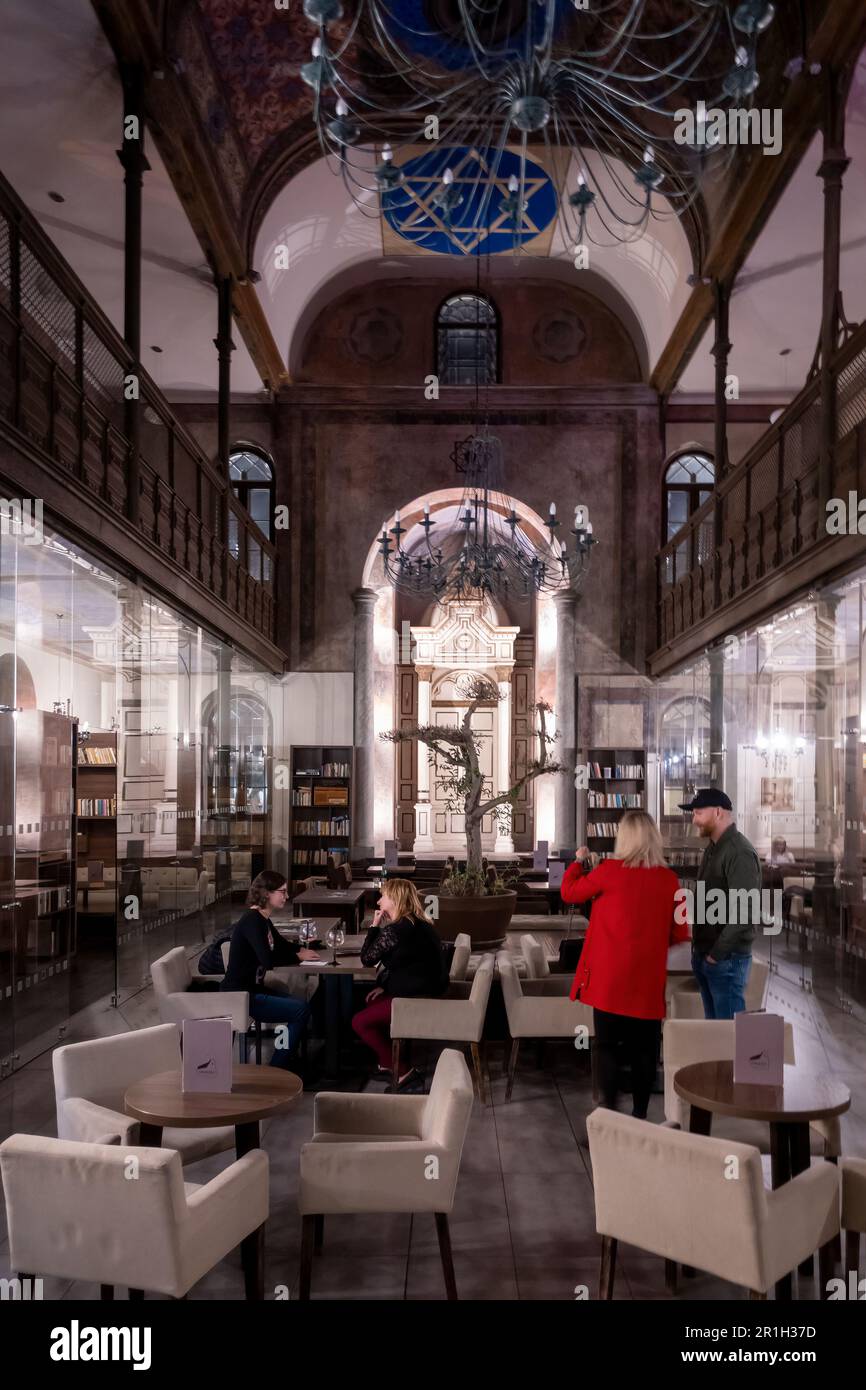 People sit inside a stylish coffee shop called "Synagoga Cafe" used to ...