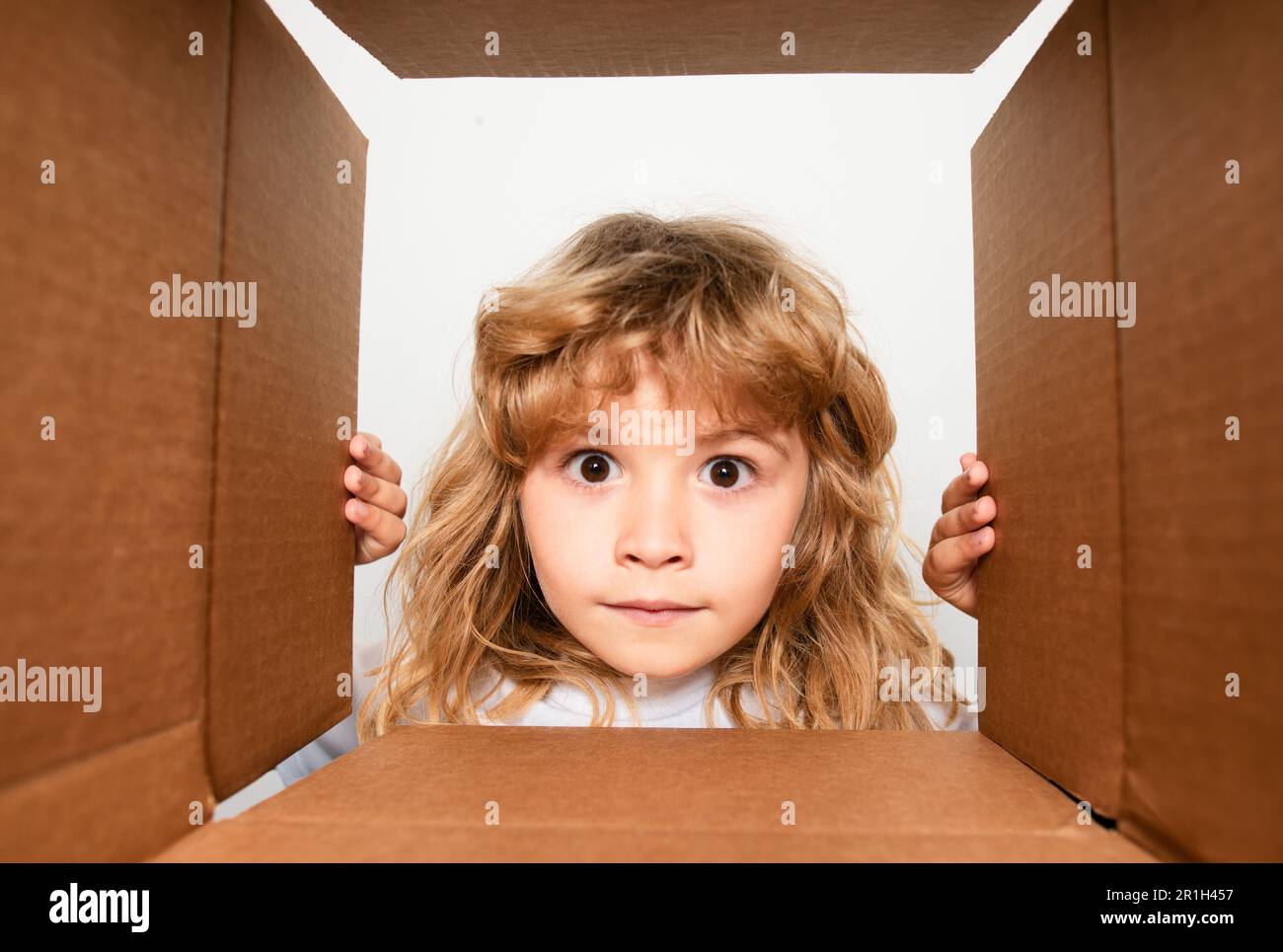 Surprised kid unpacking and opening carton box, and looking inside with ...
