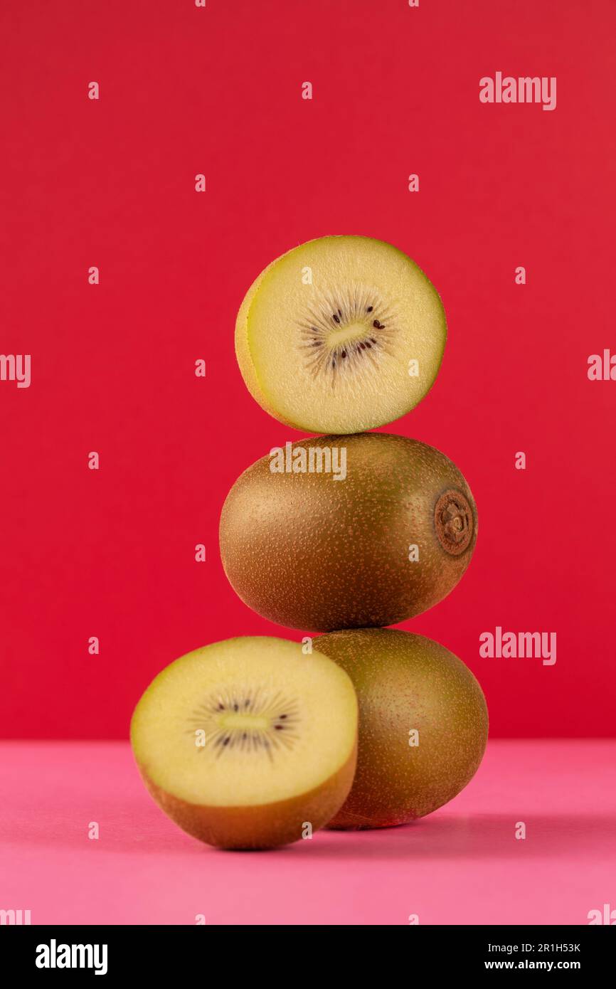 Still life of balancing golden kiwis on a red background. The concept ...