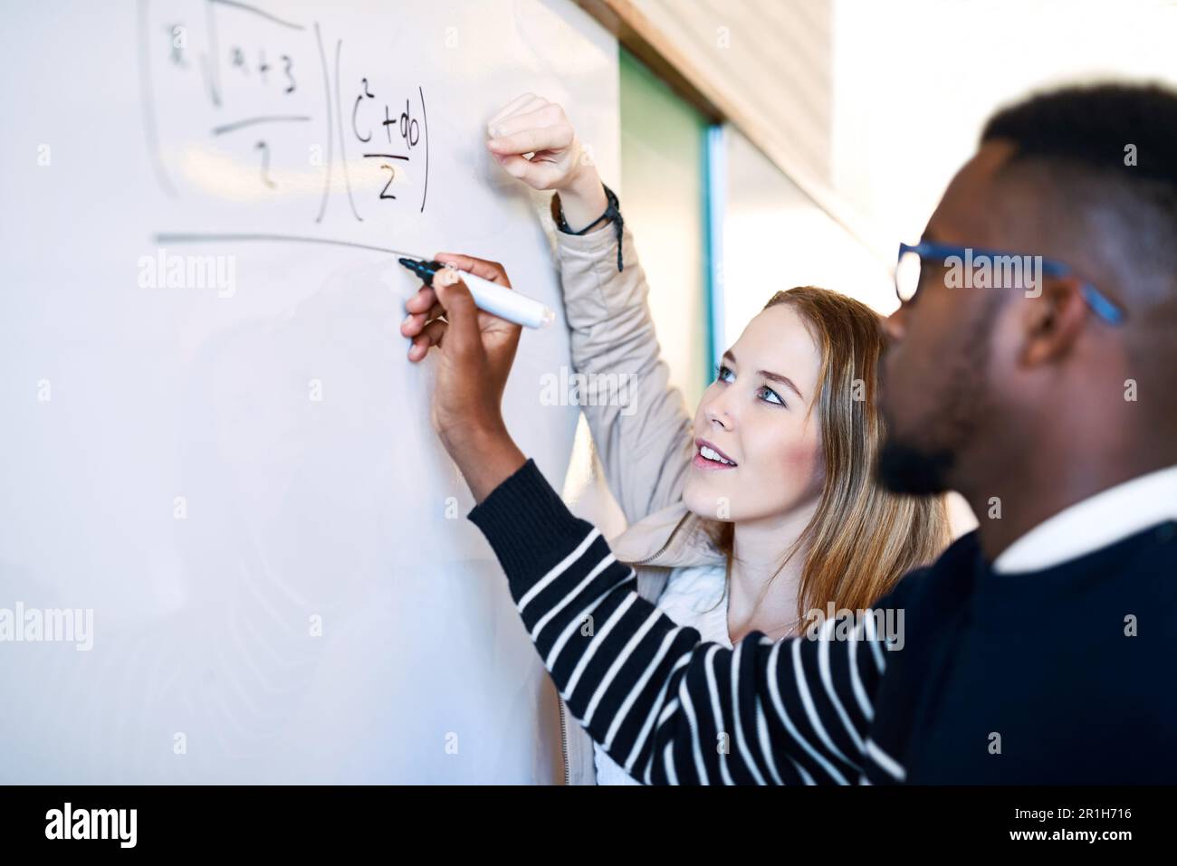 Sharing an important technique. a young man writing on a whiteboard ...