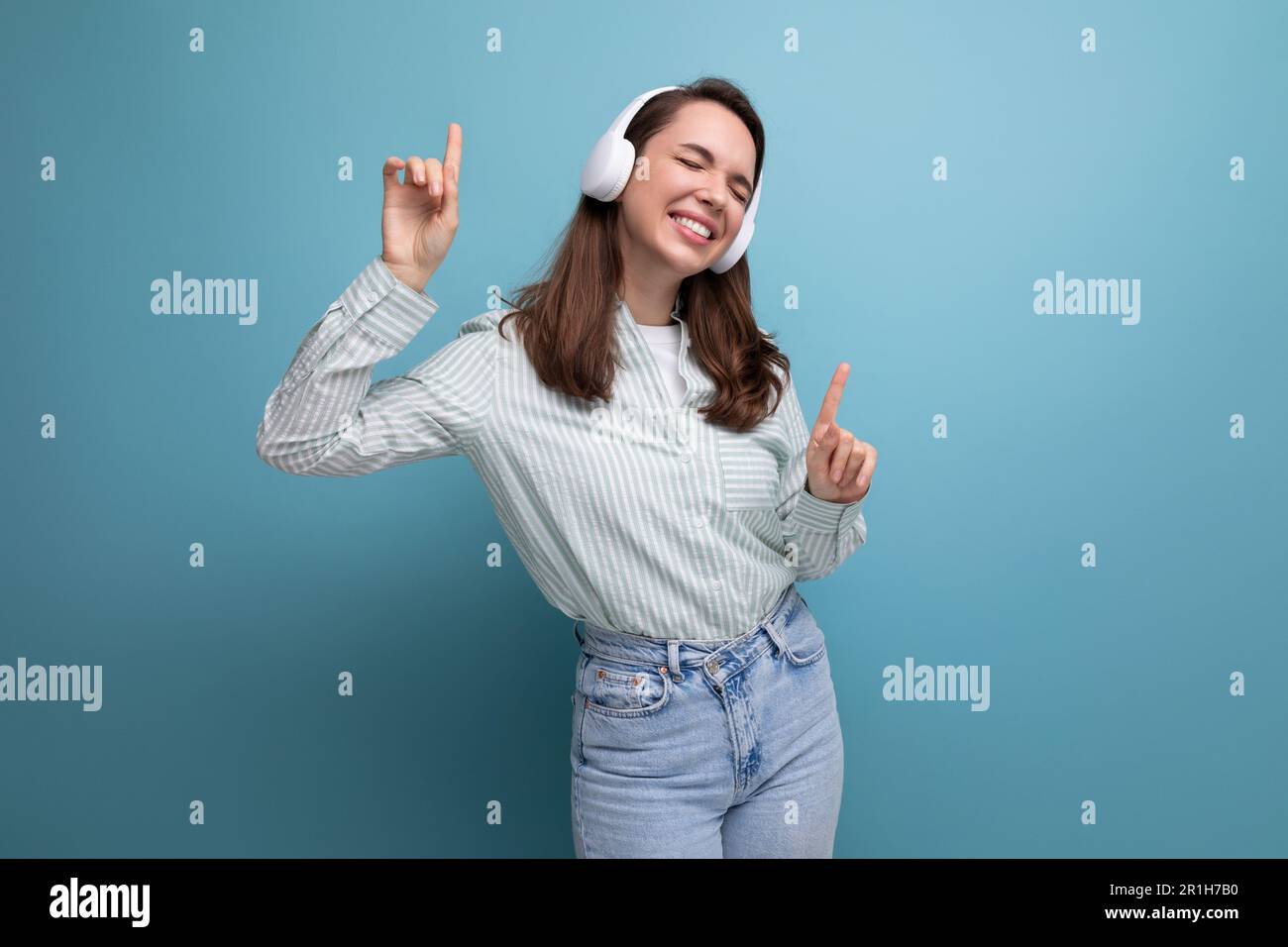 energetic pretty cute brunette young woman in shirt listening to music ...