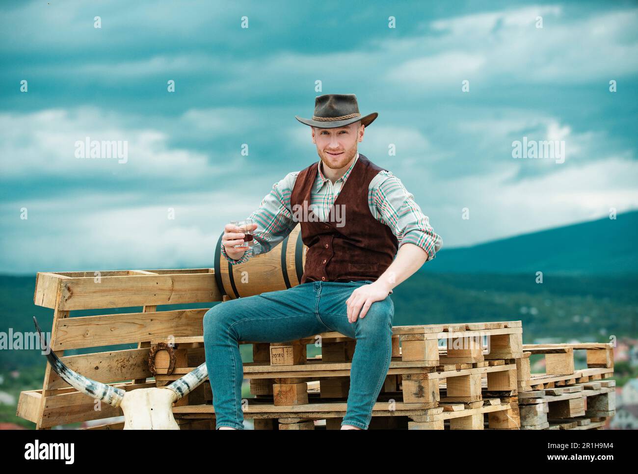 Cowboy farmer man drinks a whiskey in country side wearing western ...