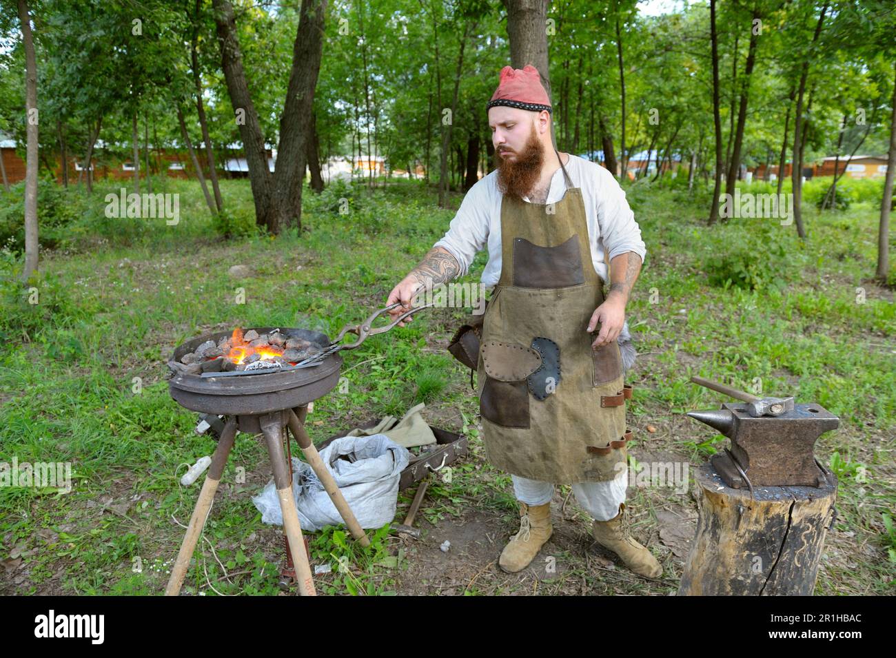 Man blacksmith dressed like ancient slavic smith forging a piece of ...