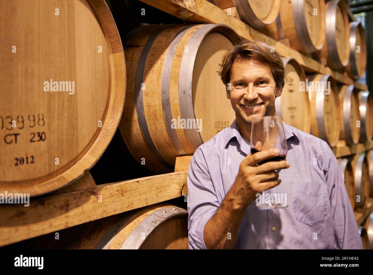 Portrait, smile and wine tasting with a man in the cellar of a ...