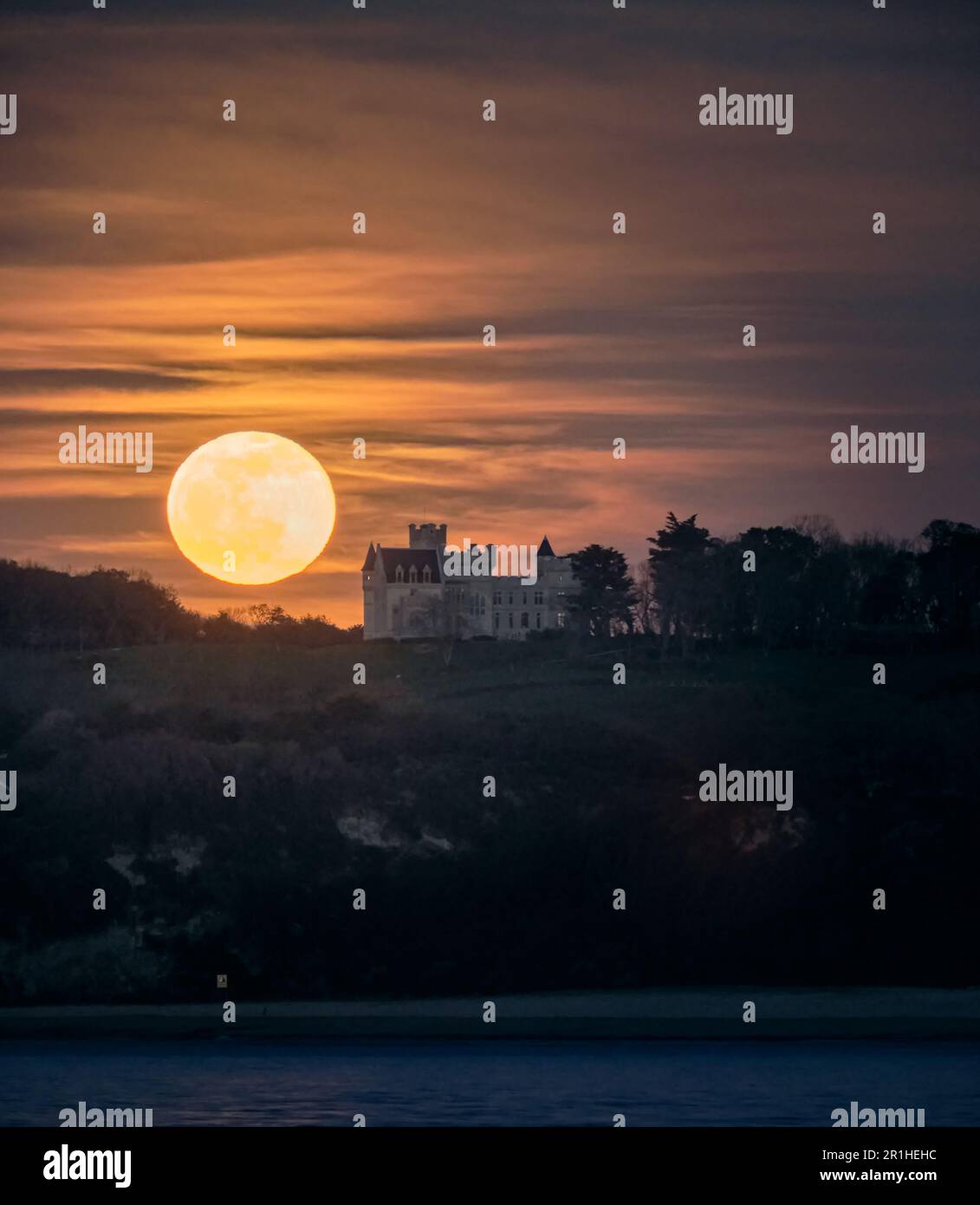 large full moon captured during dusk next to a castle on the french ...