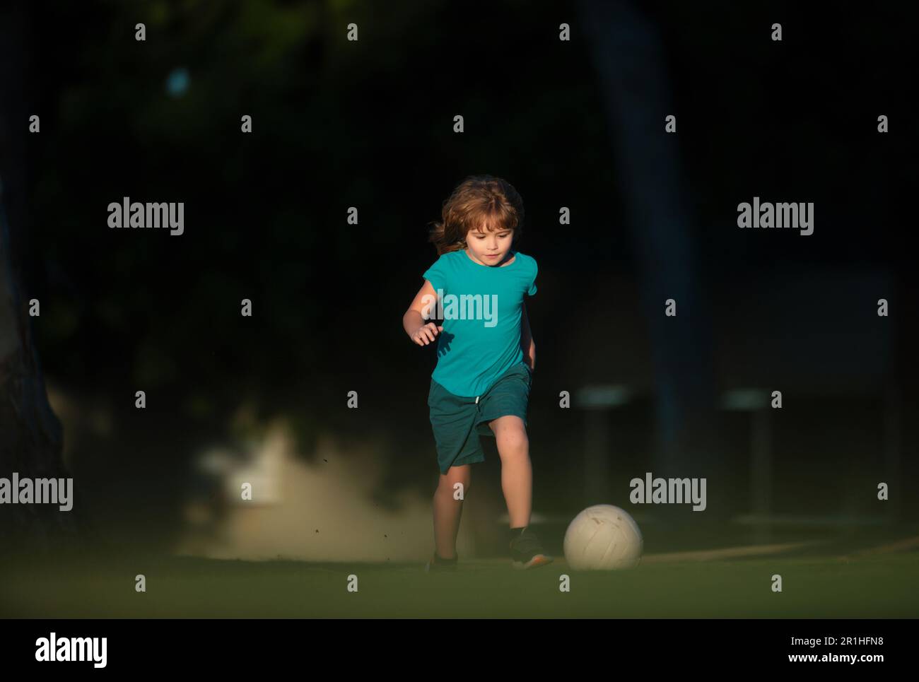 Child playing football on the playground in park. Boy child kicking ...