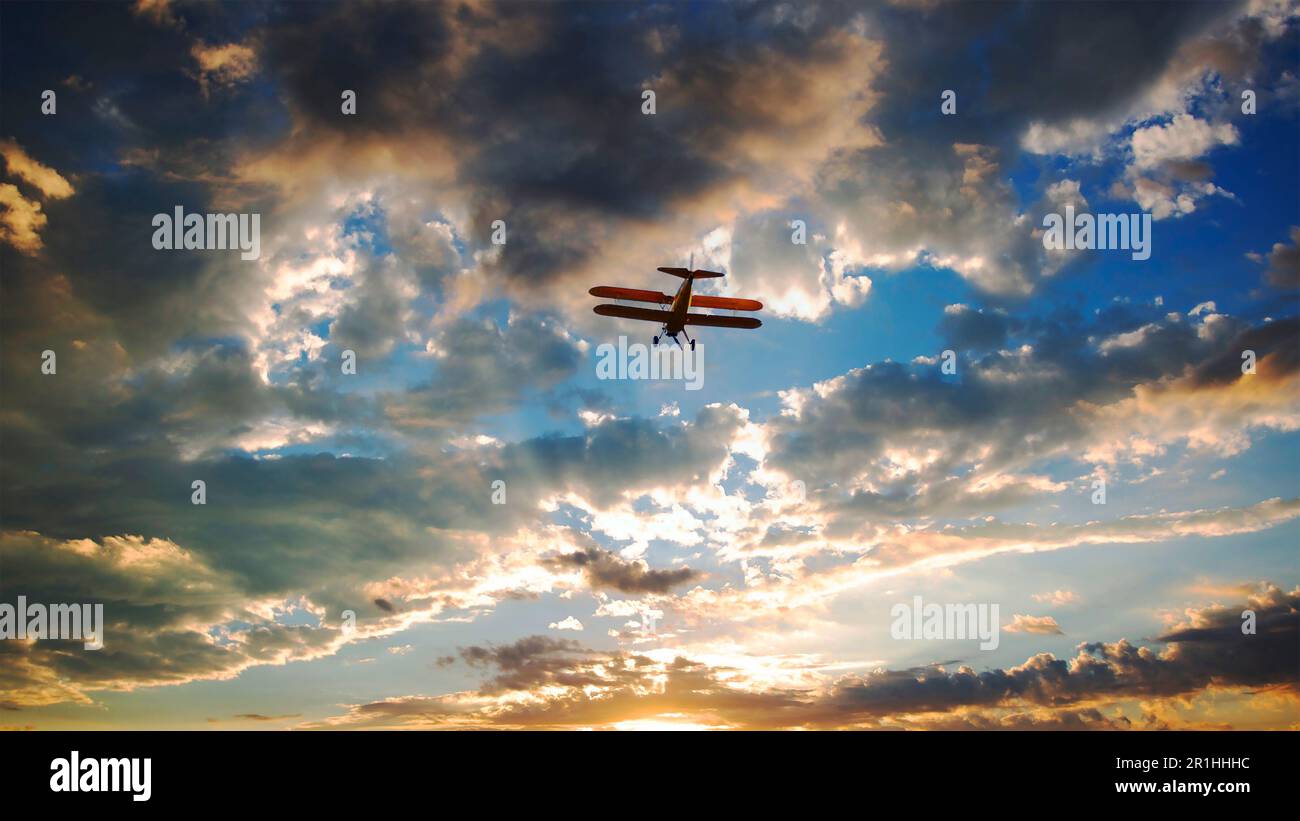 Composite of a yellow biplane flying into a cloudy sunset sky with room ...