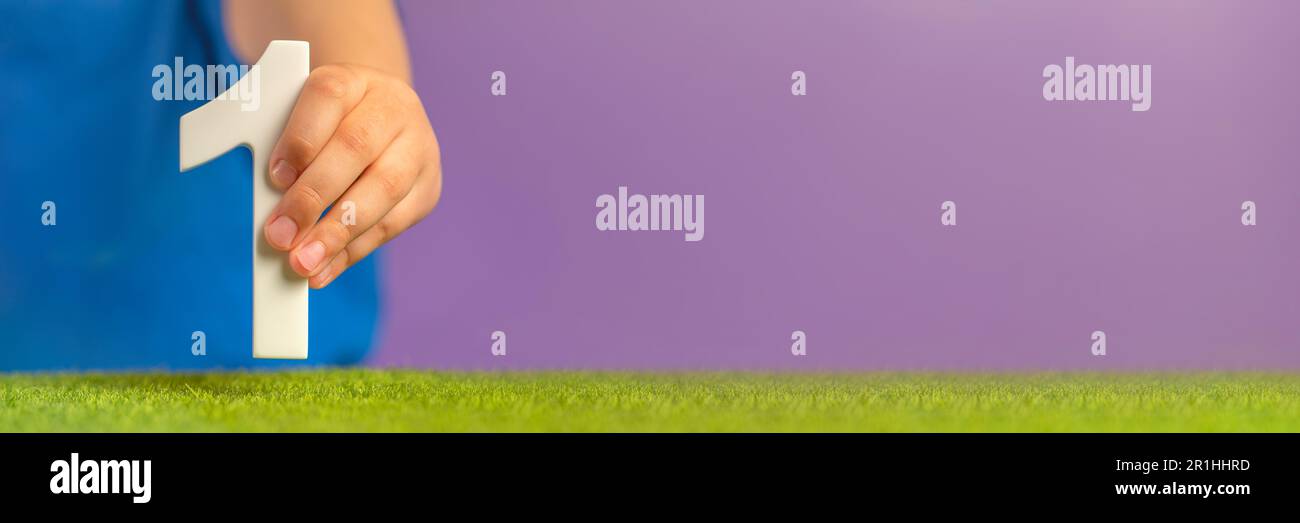 Banner with hand holding number one on green grass and purple ...