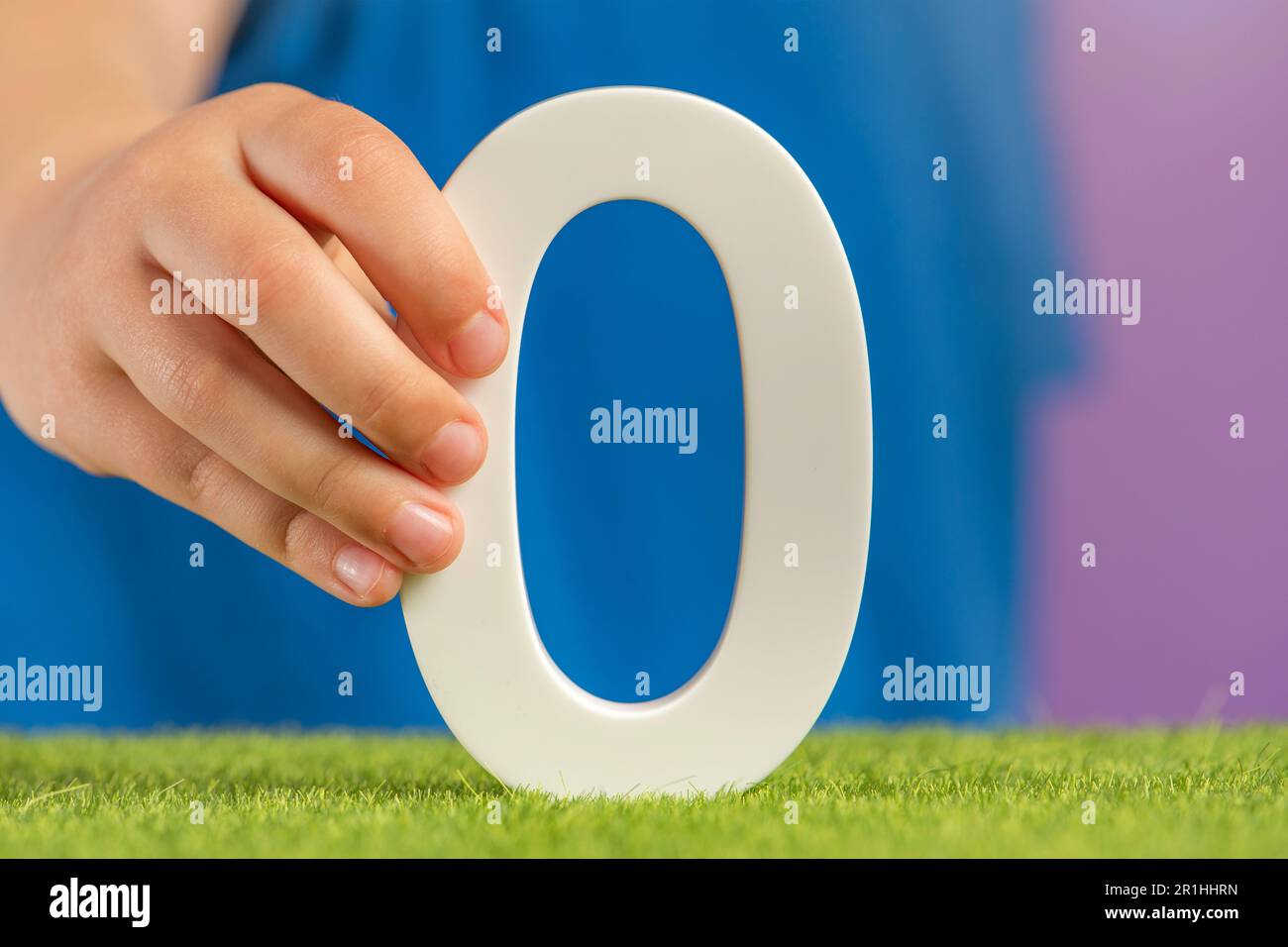 Zero emission concept. A hand holds a white number zero on green grass ...