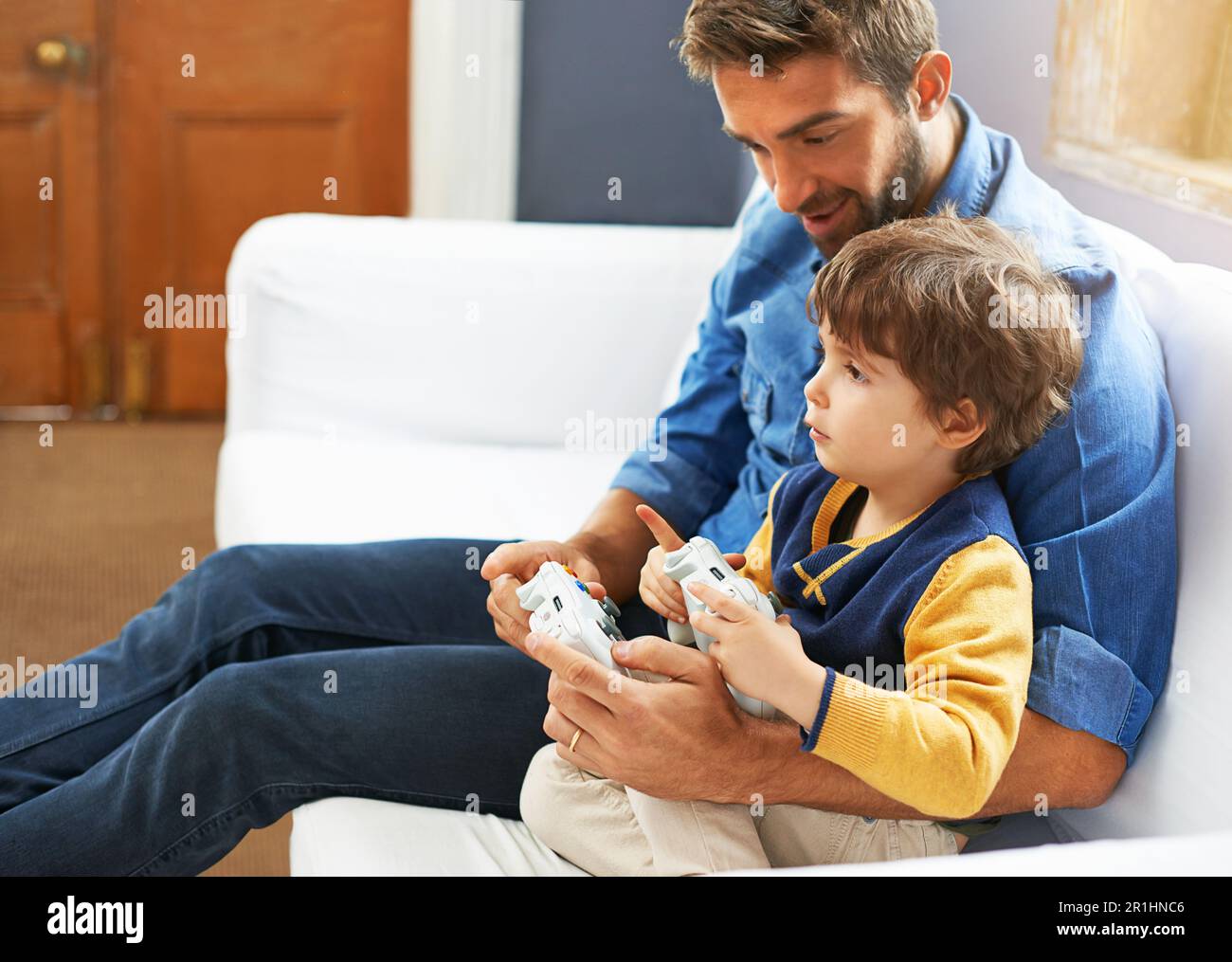 Gaming, dad and son on a sofa, playful and bonding with fun, happiness ...