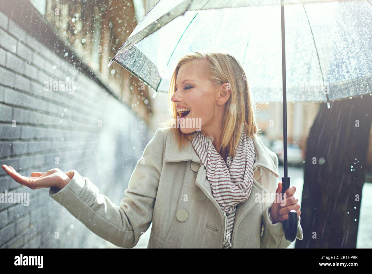Smile, happy woman and rain feeling water in the city with umbrella ...