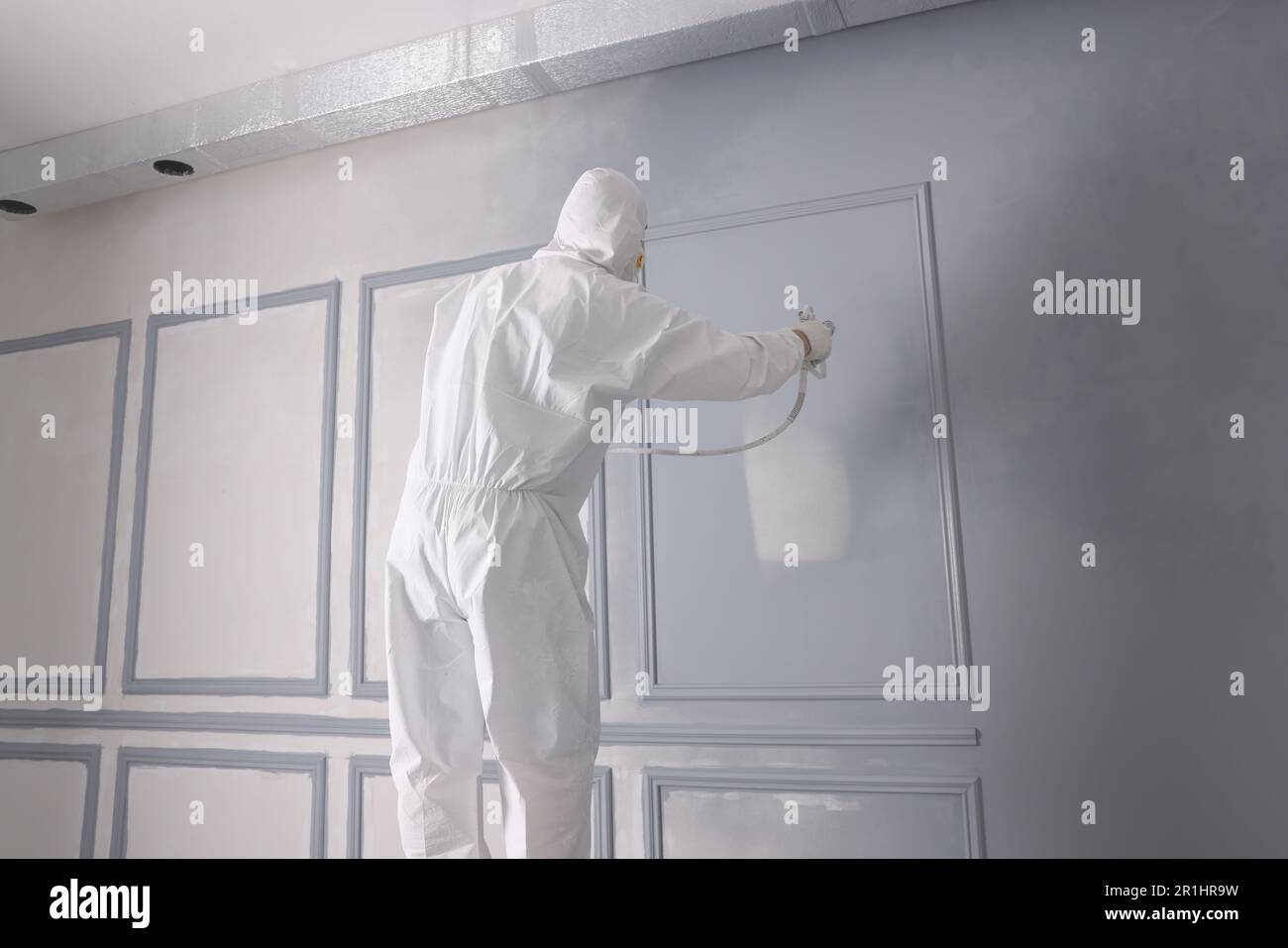 Decorator dyeing wall in grey color with spray paint Stock Photo - Alamy