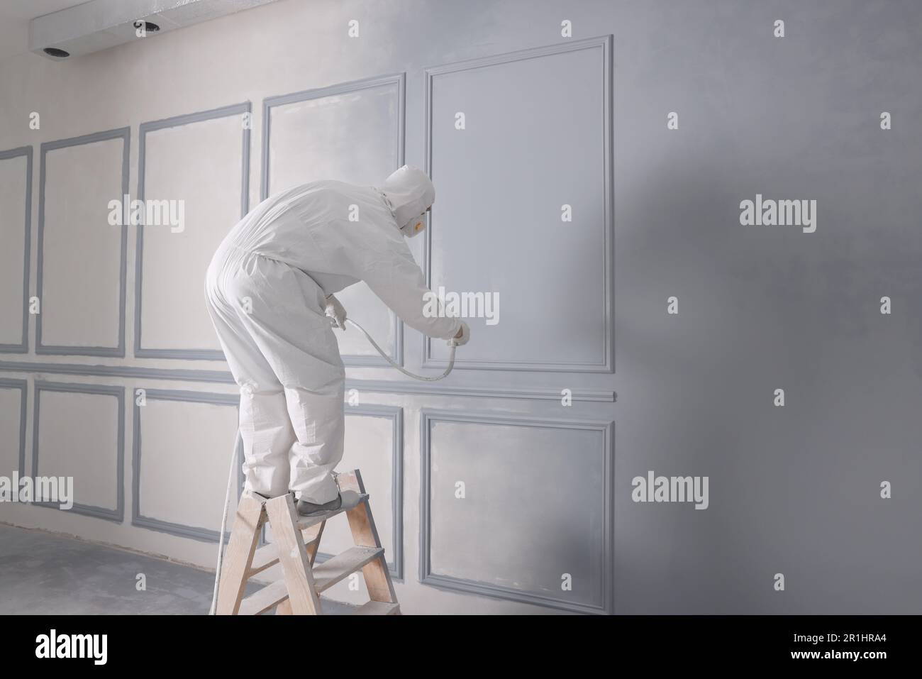 Decorator dyeing wall in grey color with spray paint Stock Photo - Alamy