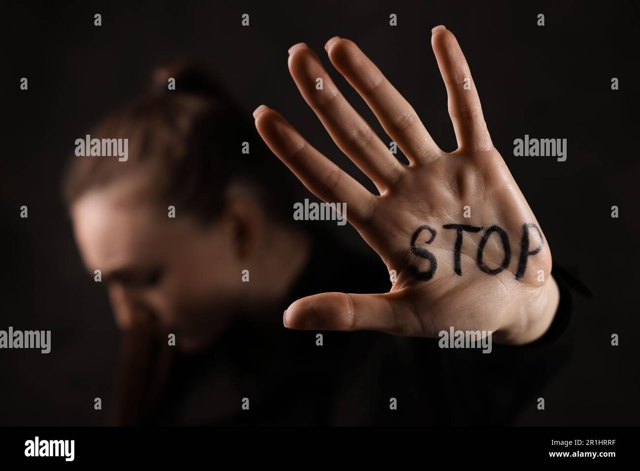 Woman with word Stop written on hand against dark background, closeup ...