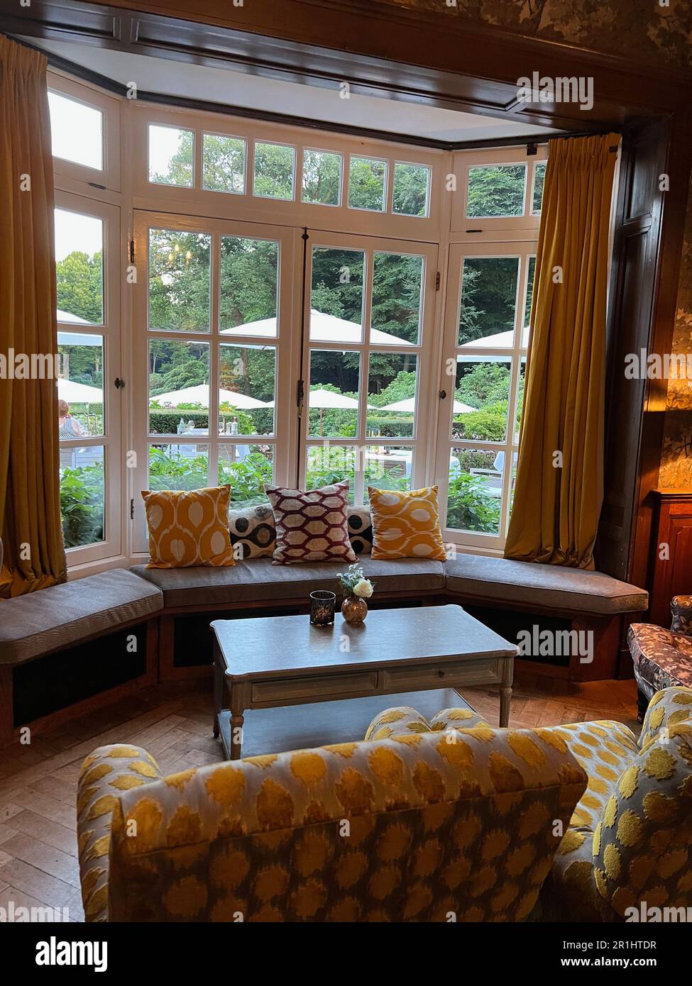 Wooden table near bay window seat with cushions in cozy room. Interior ...