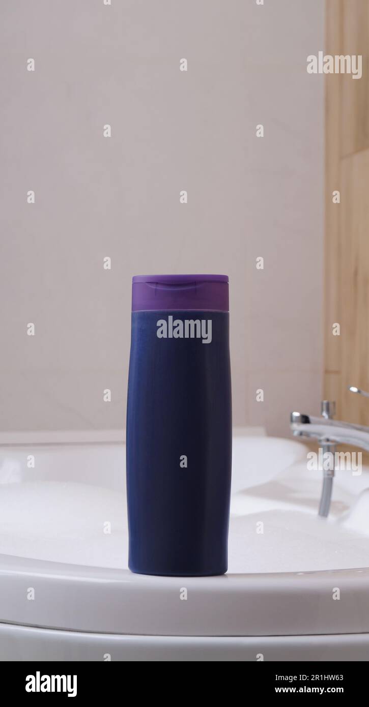 Purple bottle of bubble bath on tub indoors Stock Photo - Alamy