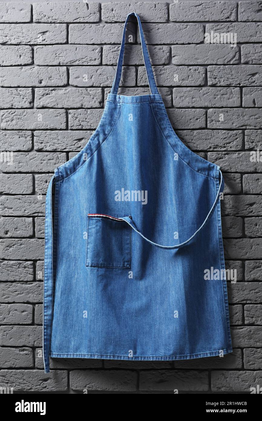Clean denim apron on grey brick wall Stock Photo - Alamy