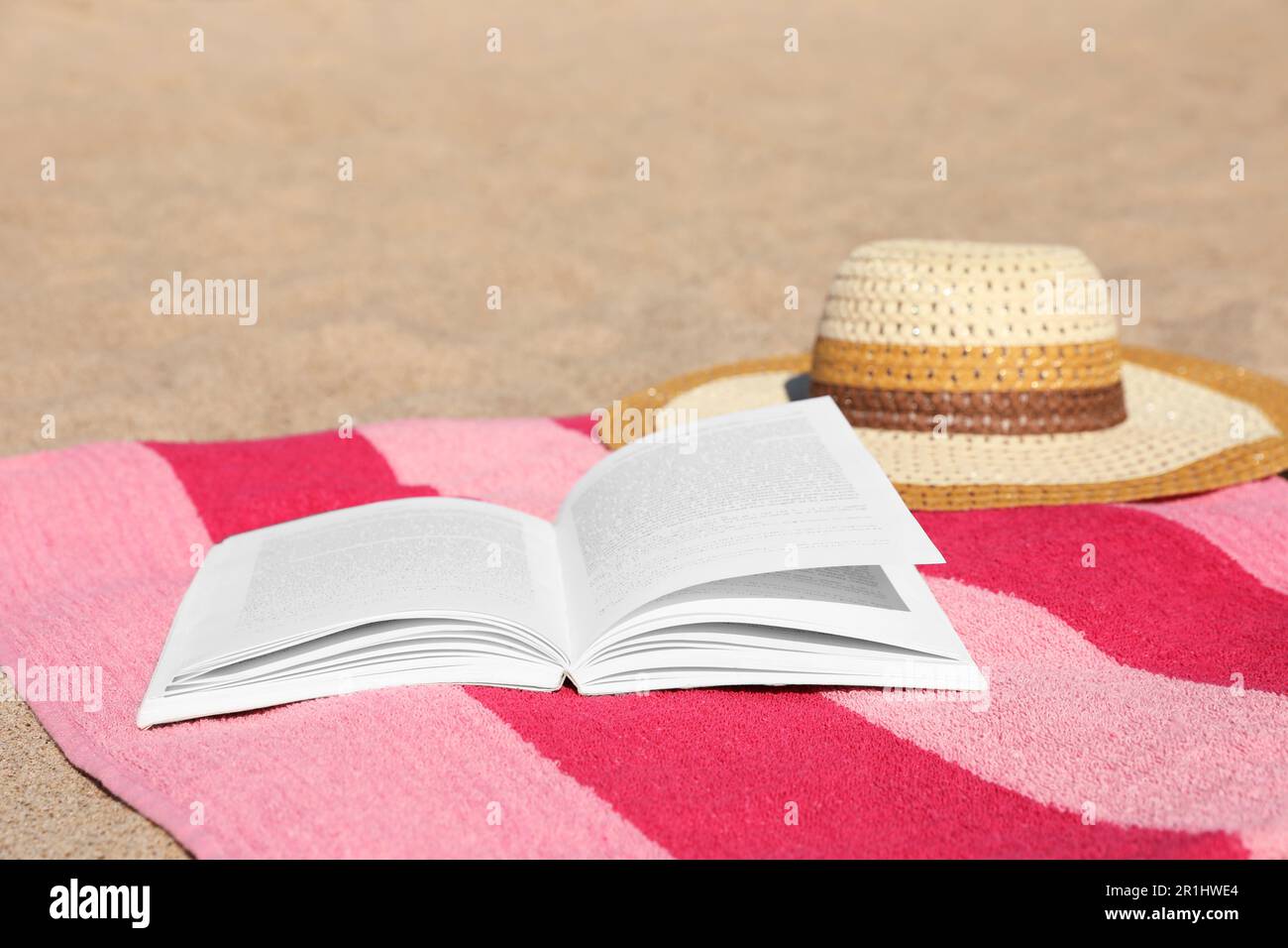 Open book, hat and striped towel on sandy beach Stock Photo - Alamy