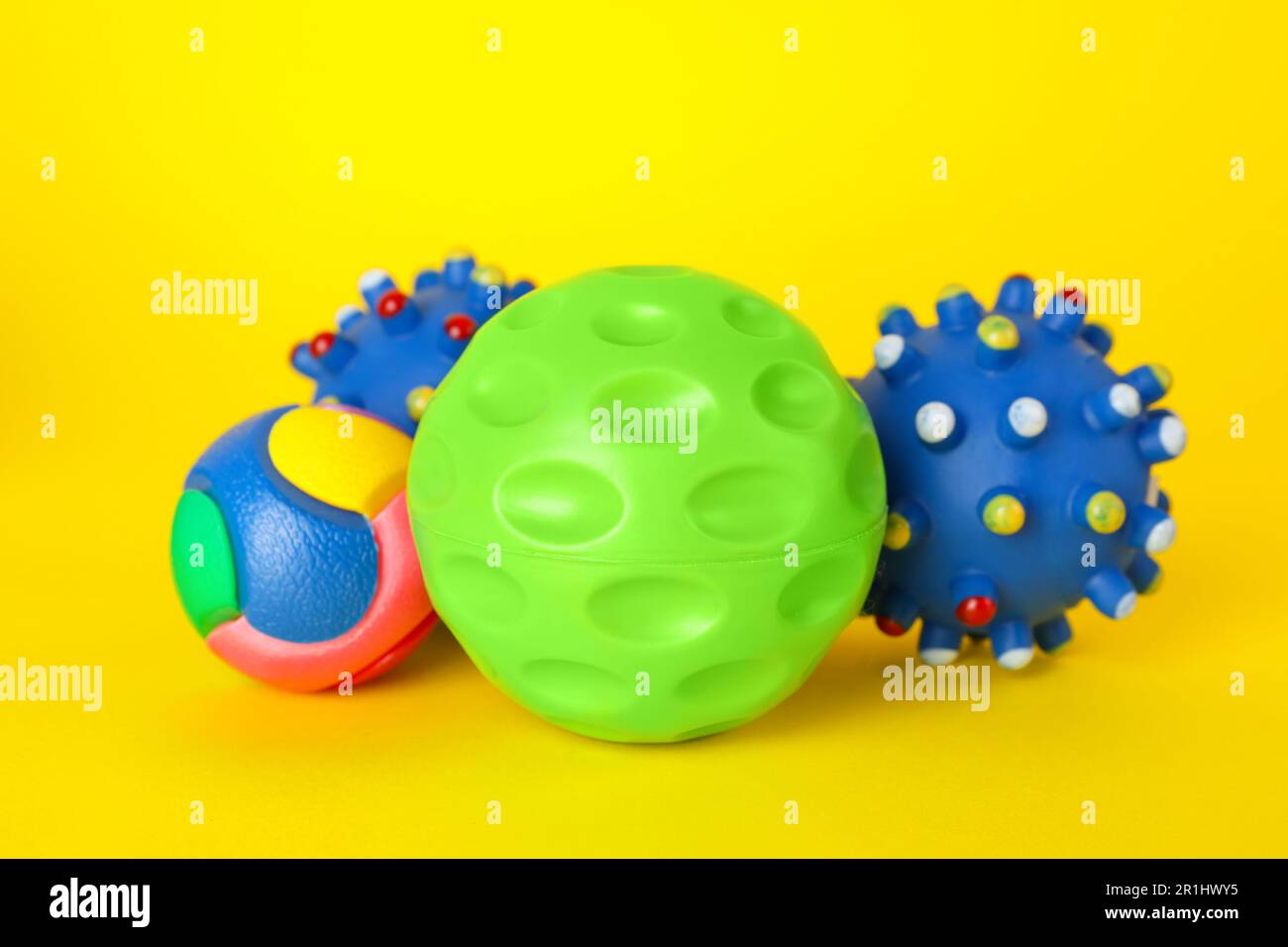 Toy balls and bone for pet on yellow background Stock Photo - Alamy