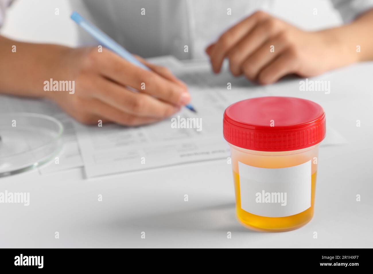 Closeup view of nurse writing urine analysis results at table, focus on ...