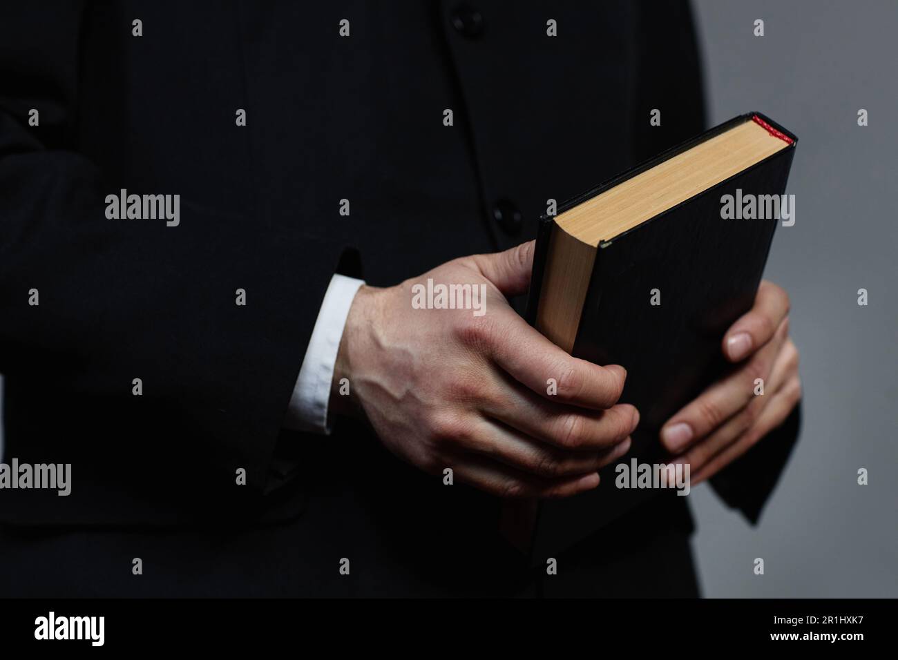 Close-up of pastor in black suit holding Bible book during sermon in ...