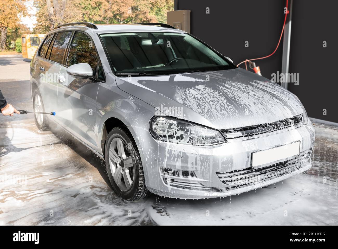Man washing auto with high pressure water jet at outdoor car wash ...