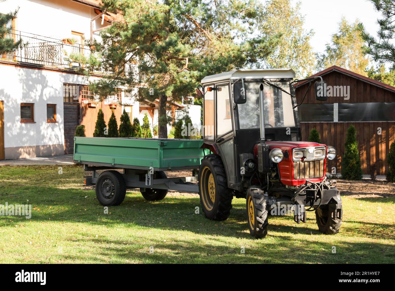 Modern tractor with empty trailer on green lawn outdoors Stock Photo ...