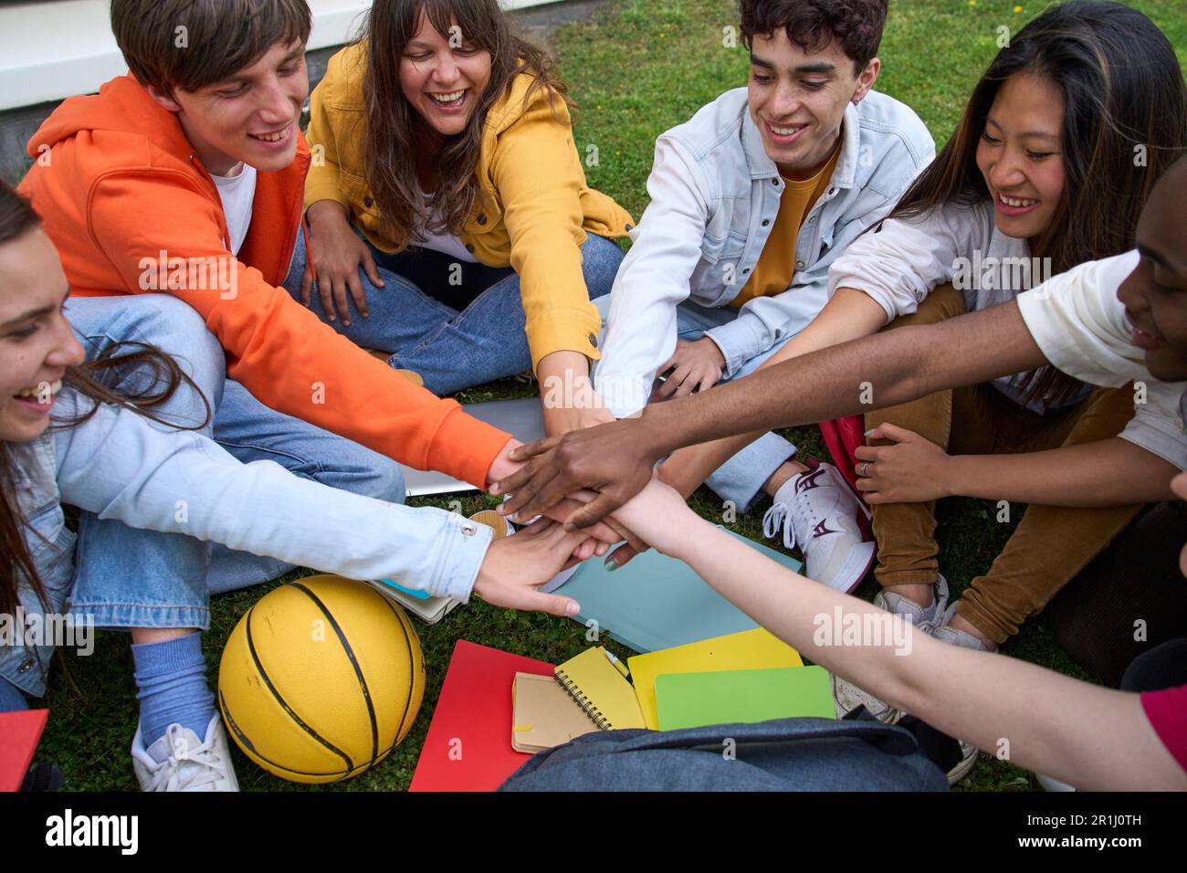 Multiracial group of cheerful young students joining hands in circle ...