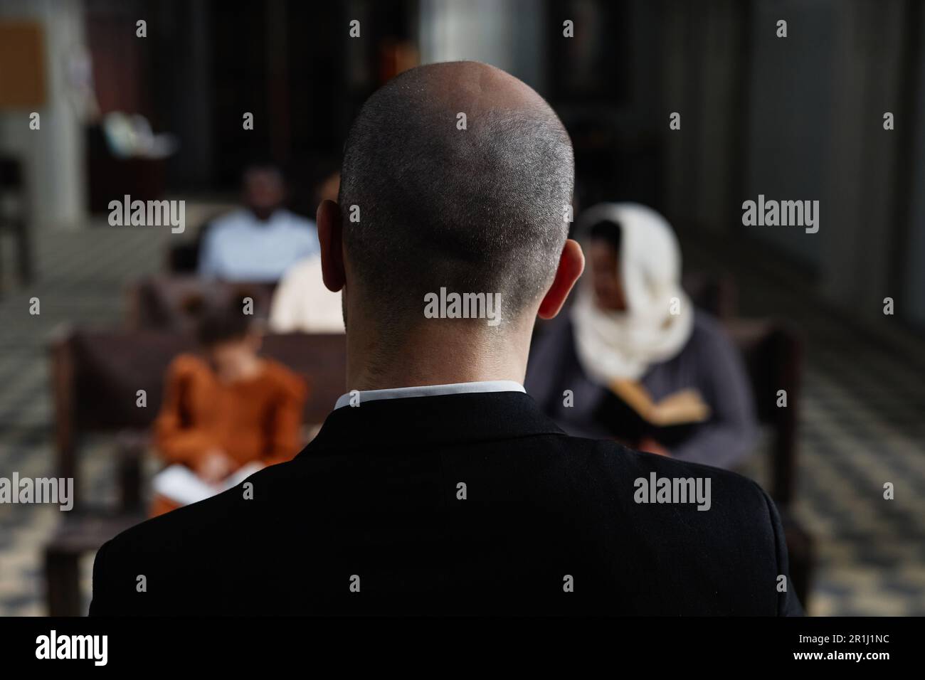 Rear view of protestant in black suit reading Bible for believers while ...