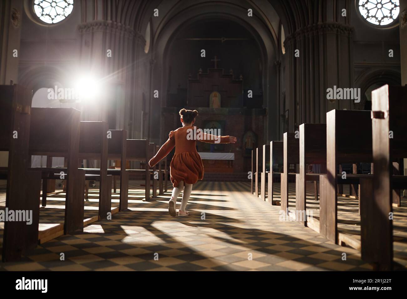 Rear view of little girl running between the benches in baptist church ...