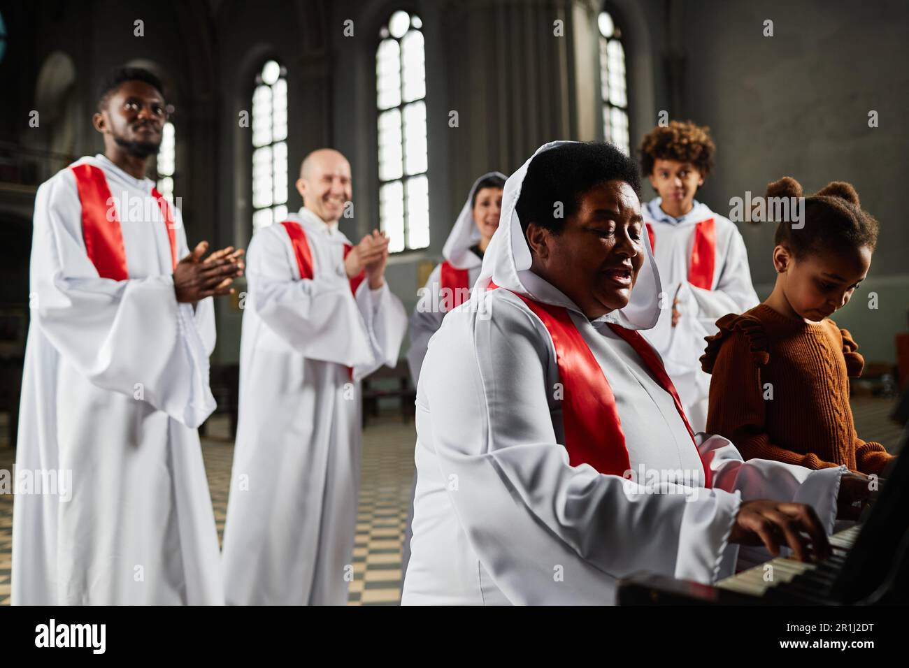 Church choir playing piano and singing together with little girl during ...