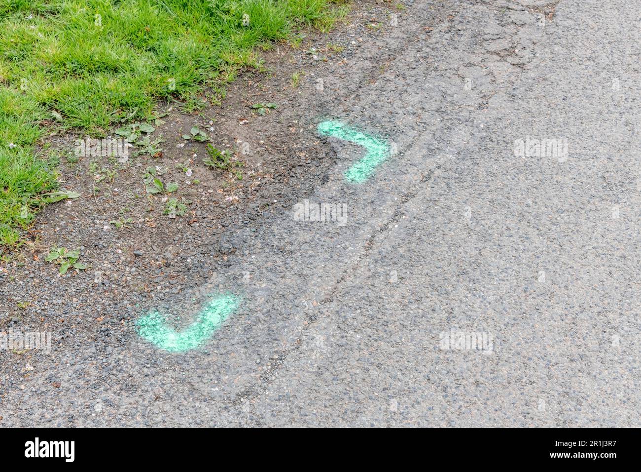 Green spray-painted markings on tarmac surfaced small road. For UK road ...