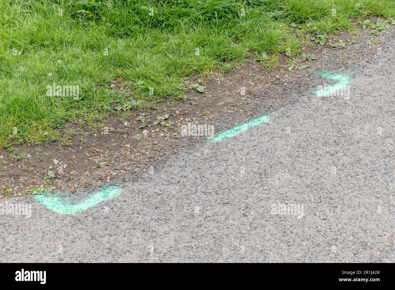 Green spray-painted markings on tarmac surfaced small road. For UK road ...