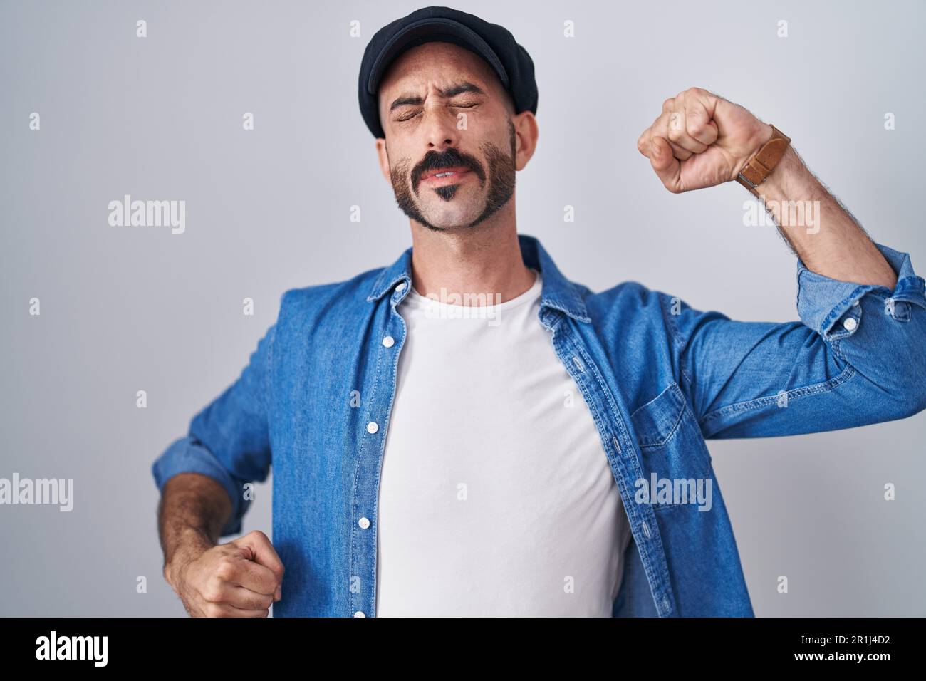Hispanic man with beard standing over isolated background stretching ...