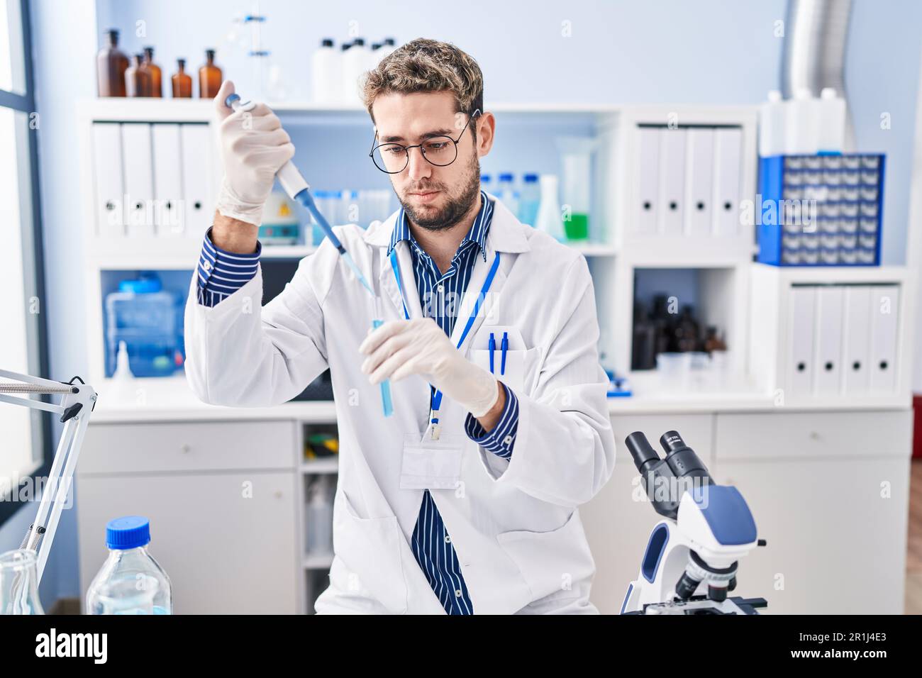 Young man scientist pouring liquid on test tube at laboratory Stock ...