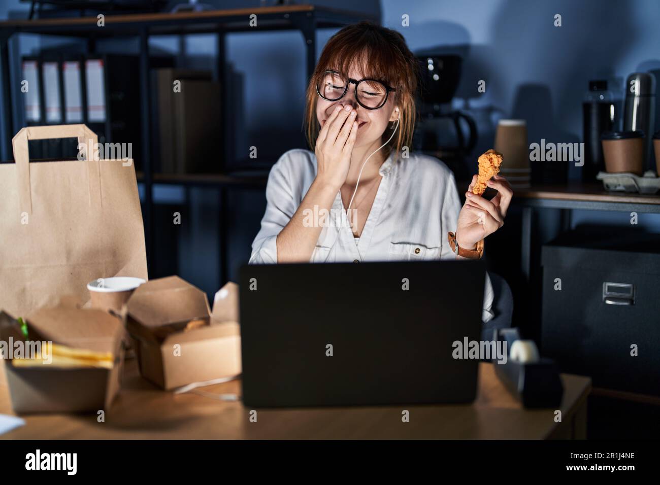 Young beautiful woman working using computer laptop and eating delivery ...