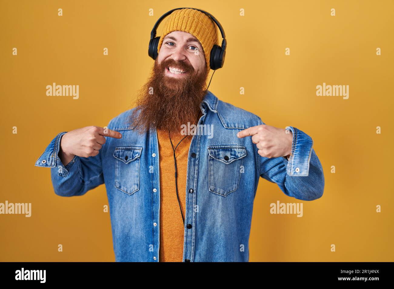 Caucasian man with long beard listening to music using headphones ...