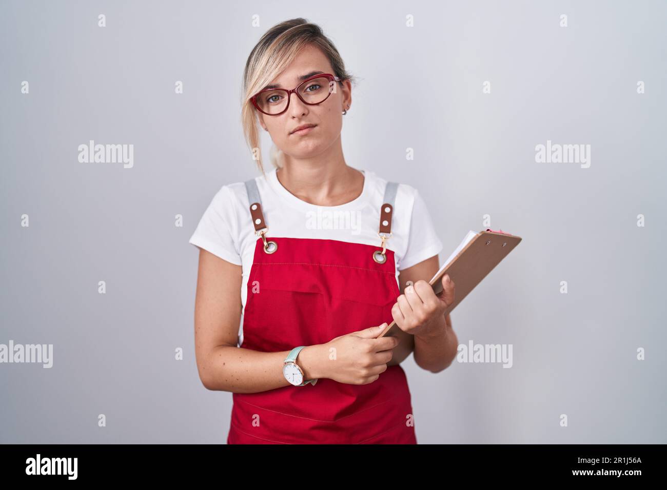 Young blonde woman wearing waiter uniform holding clipboard looking ...