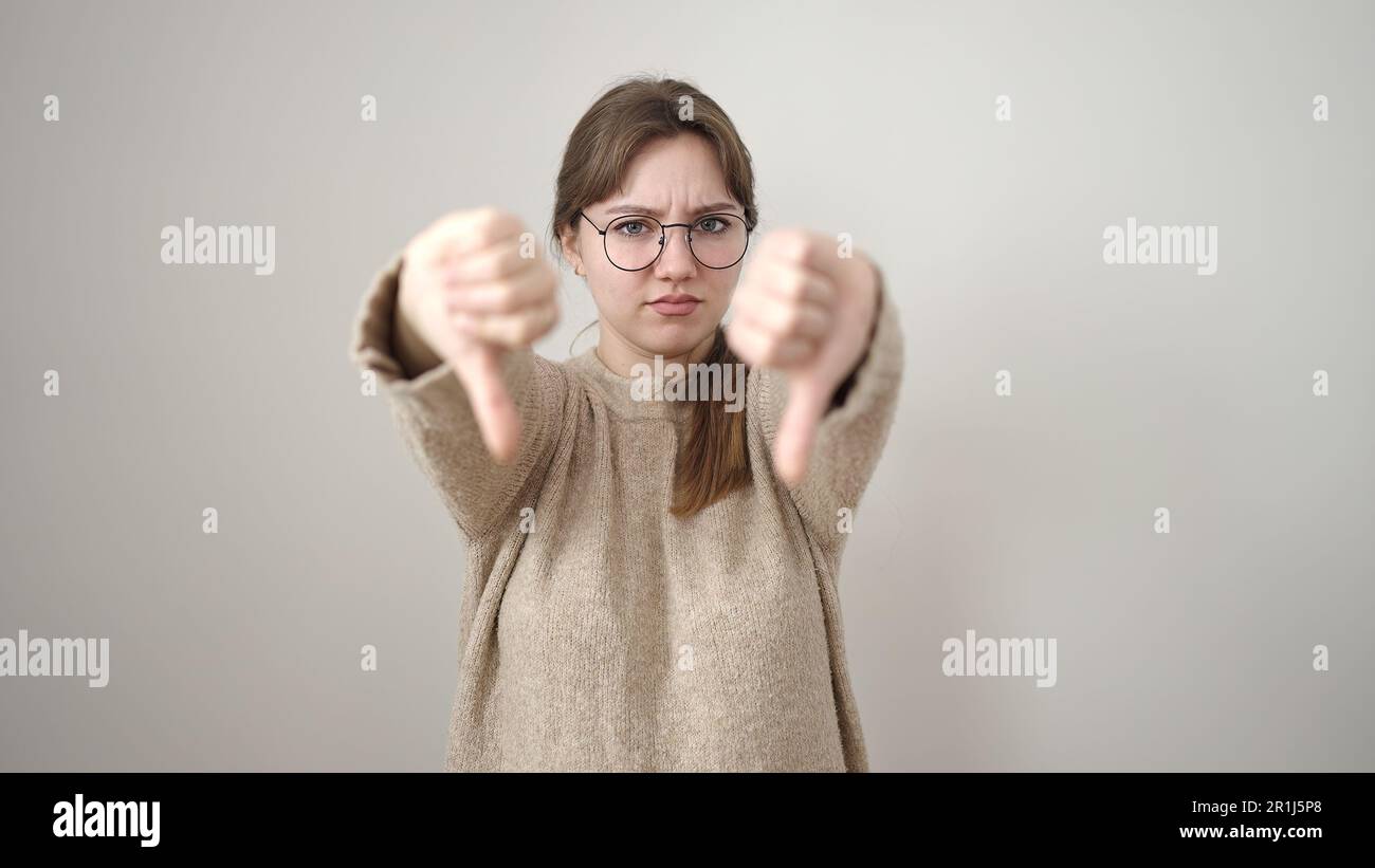 Young blonde woman doing negative gesture with thumbs down over ...