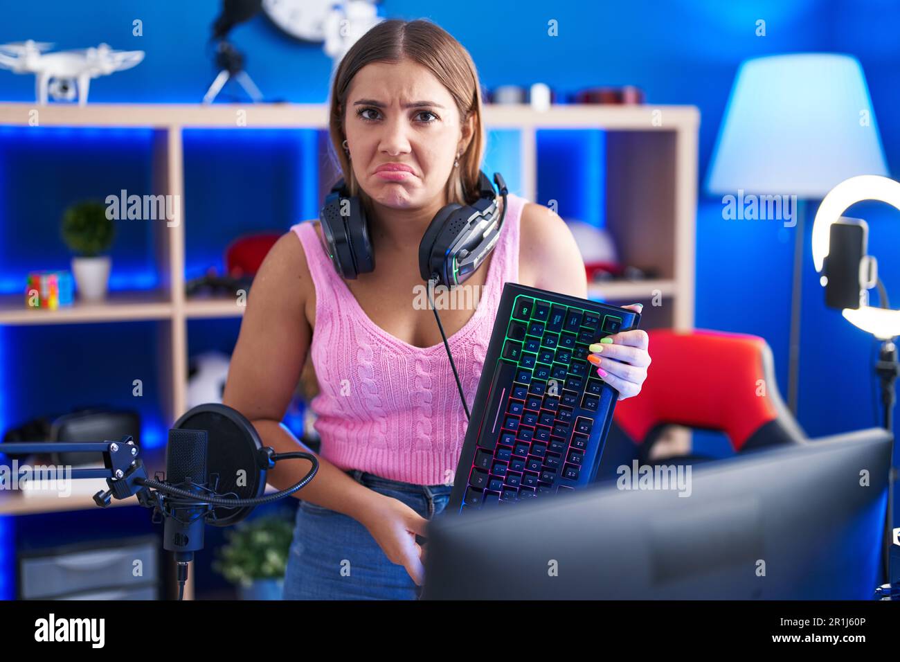 Young blonde woman playing video games holding keyboard depressed and ...