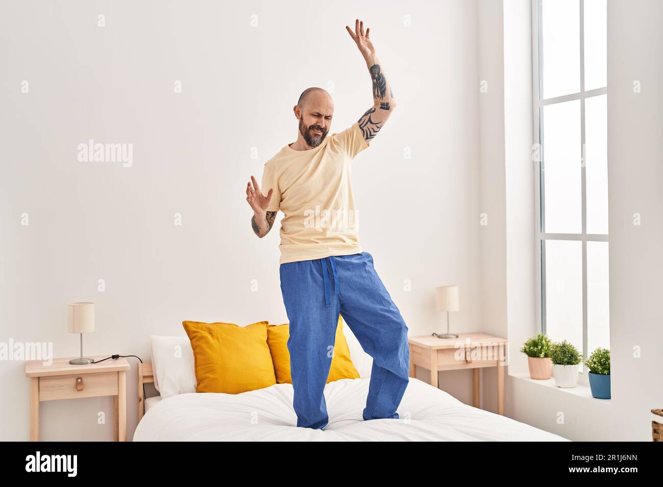 Young bald man smiling confident dancing on bed at bedroom Stock Photo ...