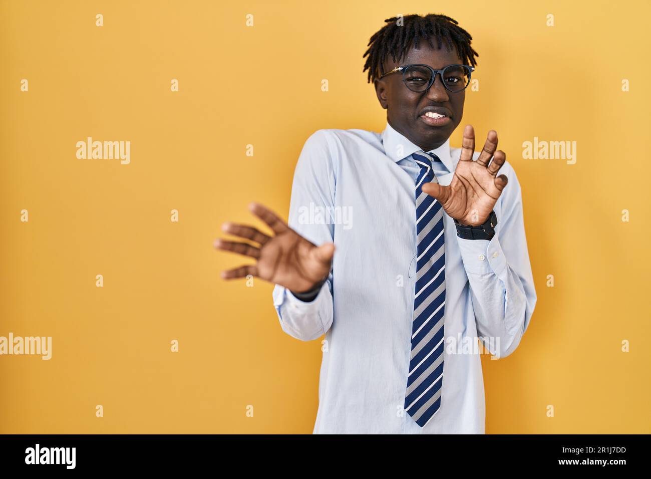 African man with dreadlocks standing over yellow background disgusted ...